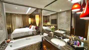Um banheiro de hotel moderno com uma banheira grande, uma toucador com espelho, e um espelho grande refletindo o ambiente.