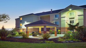 Um hotel com vários andares, um alpendre coberto, áreas de estar ao ar livre e jardins ajardinados.