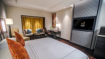 Quarto de hotel com uma cama grande, uma escrivaninha com cadeira, uma televisão e vista para a cidade.