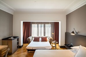 Quarto de hotel com uma cama, escrivaninha, cadeira, mesinha e abajur.