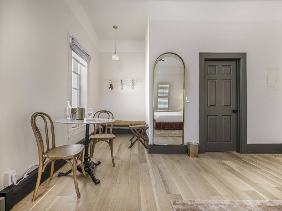 Quarto com uma mesa de jantar, cadeiras, um espelho e uma porta.
