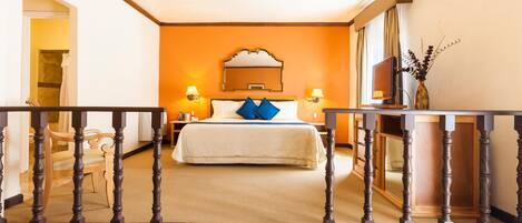 Quarto de hotel com uma cama, duas luminárias de cabeceira, uma televisão e um espelho sobre a cama.