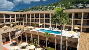 Um hotel com piscina central, área de estar externa e vários andares com varandas.