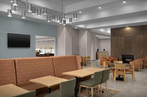 Interior moderno de restaurante com pé direito alto, iluminação pendente e uma variedade de opções de assentos, incluindo cabines e mesas.