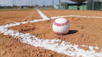 Uma bola de beisebol em um campo de terra com linhas brancas de giz.