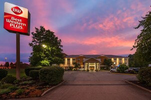 Um hotel Best Western Plus com entrada bem iluminada, estacionamento e área ajardinada.