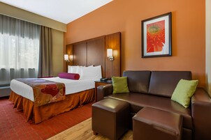 Quarto de hotel com uma cama grande, um sofá e um quadro na parede.