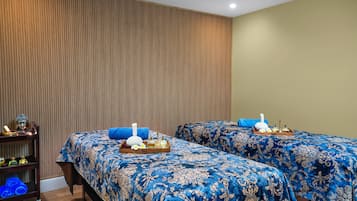 Quarto com duas camas, parede de painel de madeira e prateleira com toalhas e uma estátua de Buda.