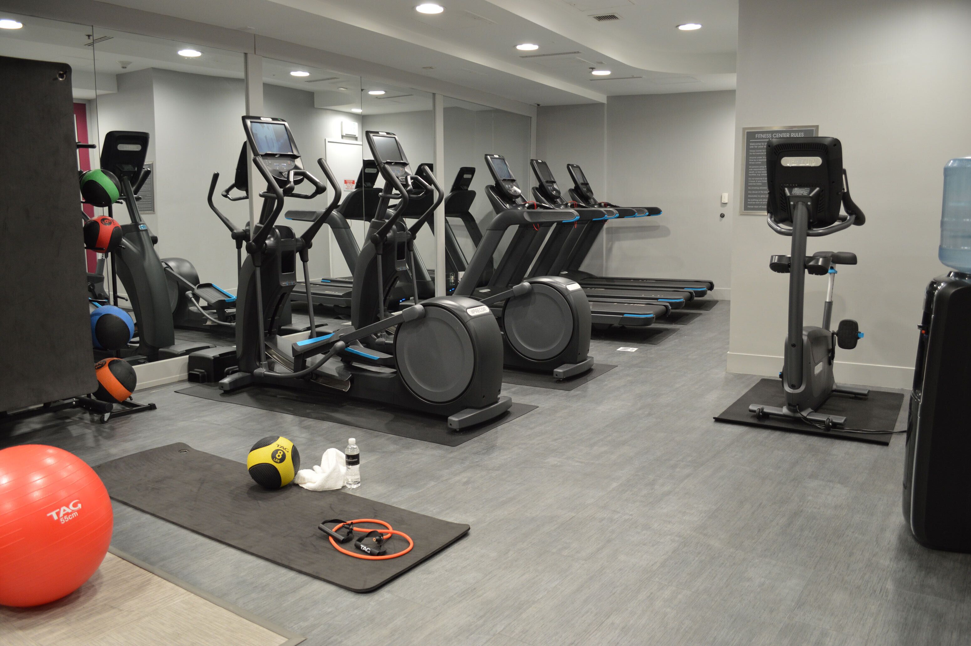 Uma academia com esteiras, elípticos e bolas de exercício.