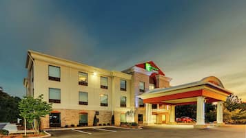 Hotel Holiday Inn Express com posto de combustível anexo, apresentando um estacionamento e uma caminhonete vermelha.