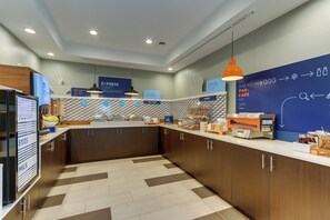 Uma área de café da manhã moderna com balcão, variedade de alimentos para o café da manhã e parede com placas de sinalização.