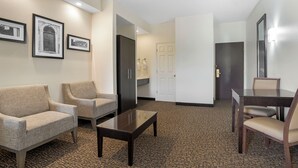 Um saguão de hotel com uma mesa de recepção, dois sofás, uma mesa de centro e uma mesa de jantar com cadeiras.