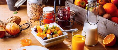 Mesa de café da manhã com frutas, pão, queijo e bebidas.