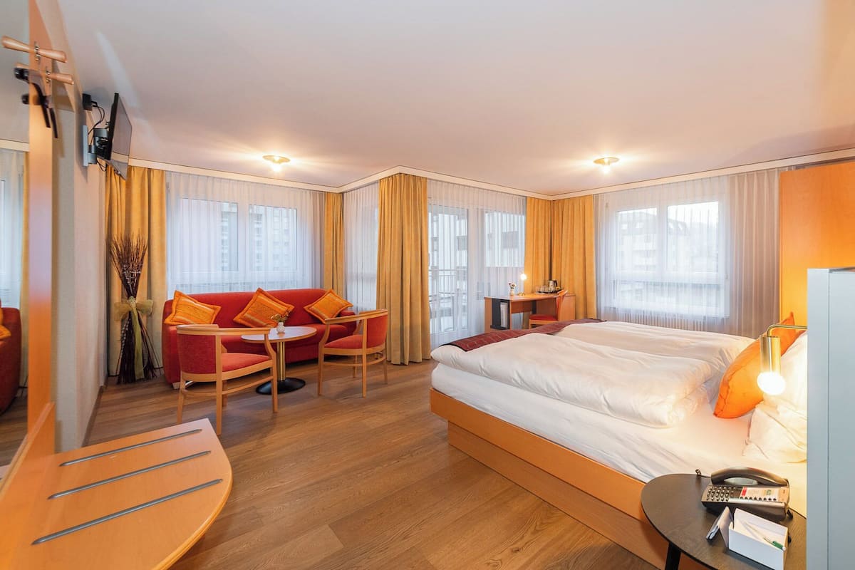 Quarto de hotel com uma cama grande, um sofá, uma escrivaninha e uma cadeira.