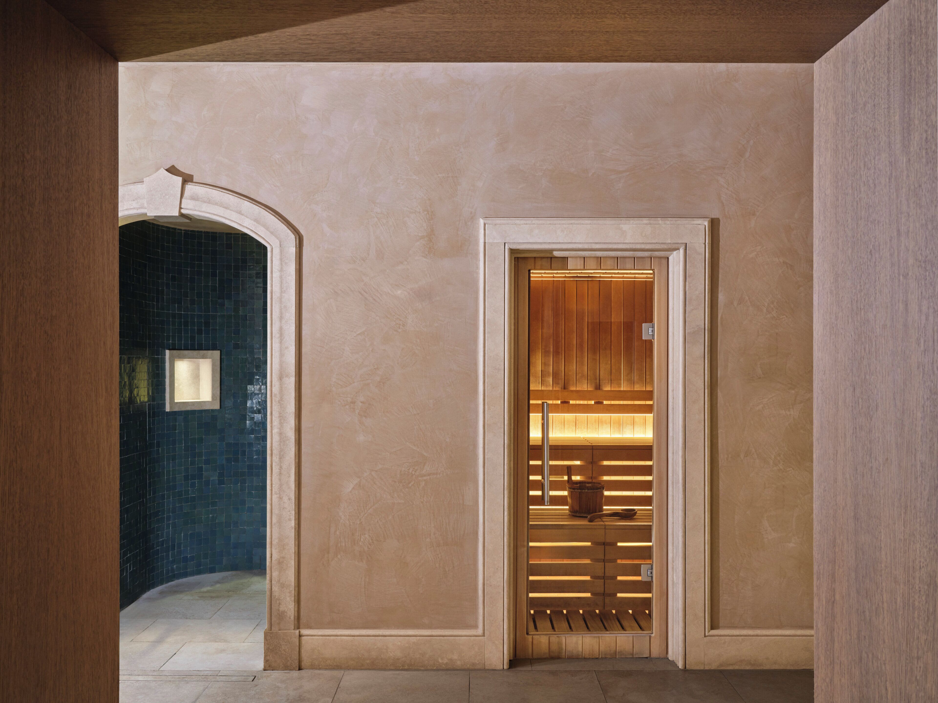 Um corredor com uma porta de madeira que dá para um quarto com sauna integrada.