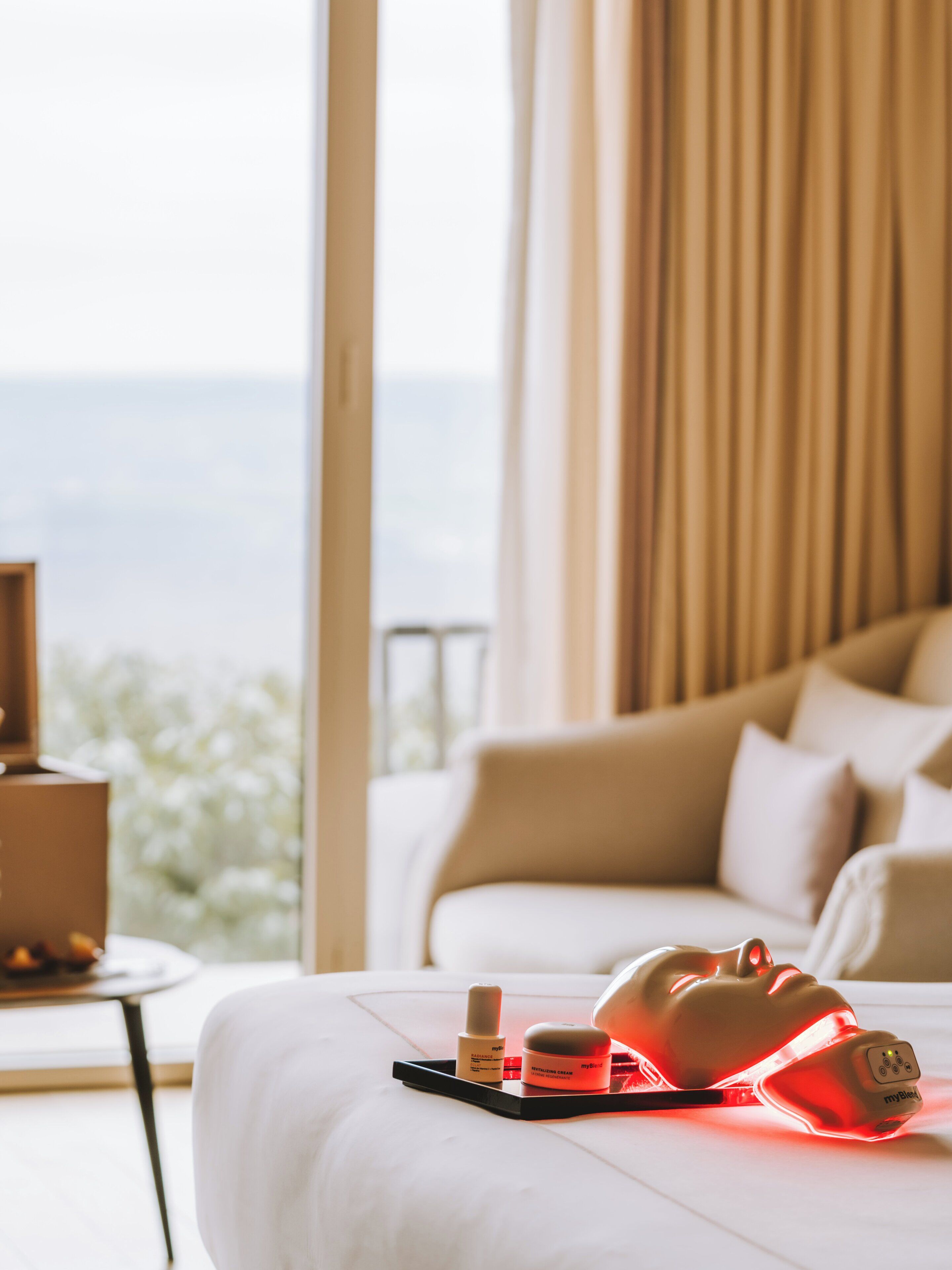 Quarto de hotel com cama, mesa de cabeceira e luminária, e vista para o exterior.