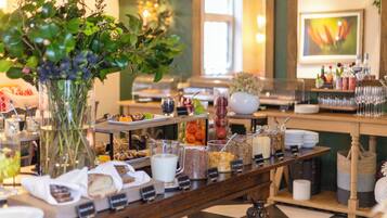 Disposição de buffet com diversos alimentos e um vaso decorativo de flores.