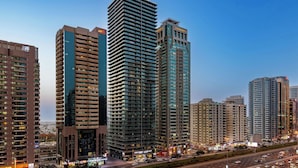 Um edifício alto com design moderno, com vários andares e fachada de vidro marcante.