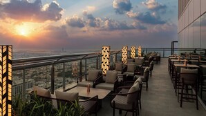 Terraço no telhado com área de estar ao ar livre, vista da cidade e pôr do sol.