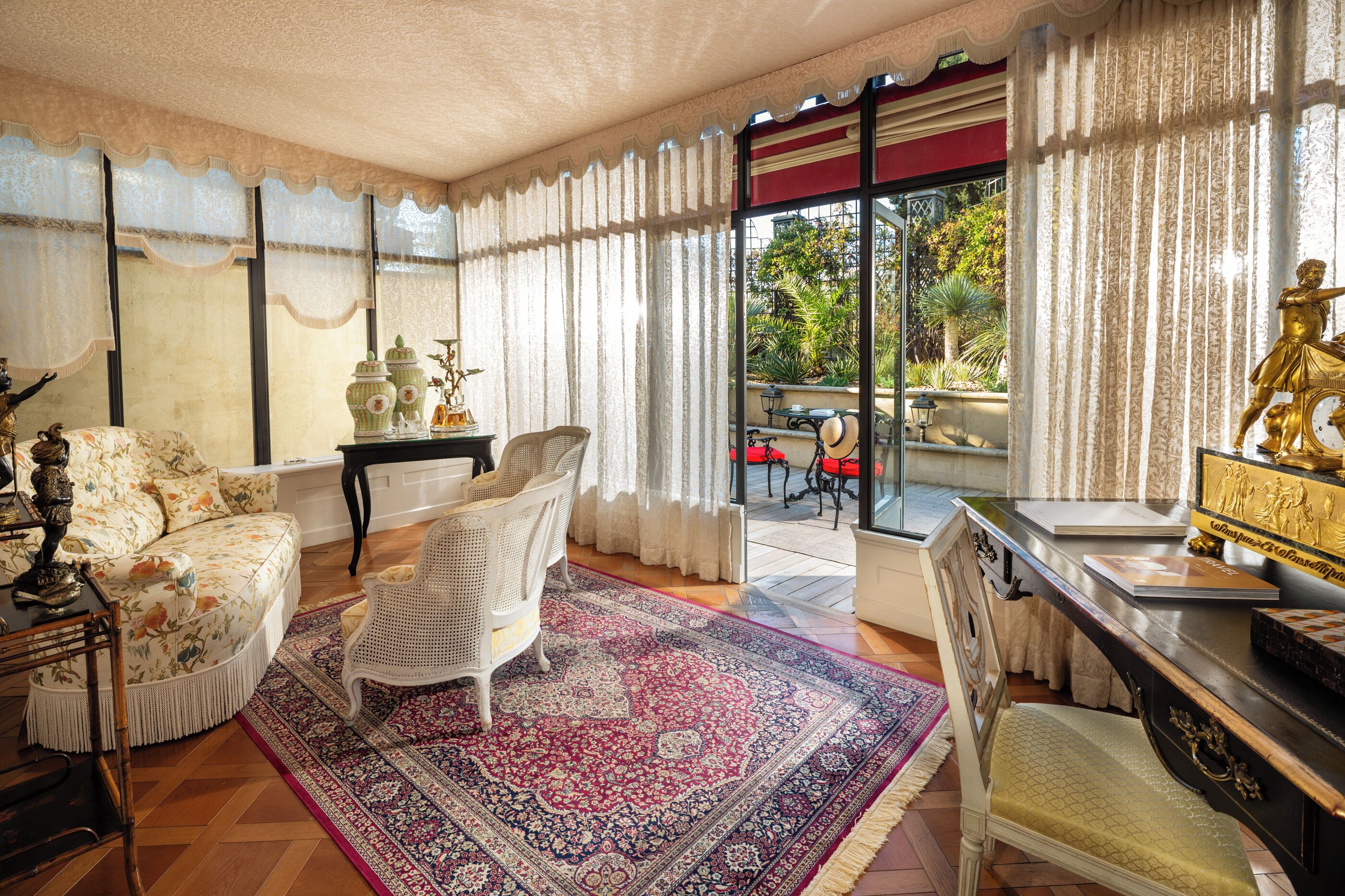 Quarto com sofá, poltronas, mesa de jantar e vista para o exterior.