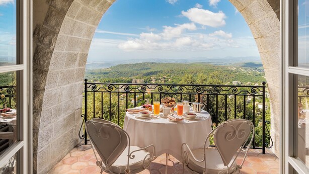 Varanda com mesa posta para o café da manhã, com vista para uma paisagem deslumbrante.