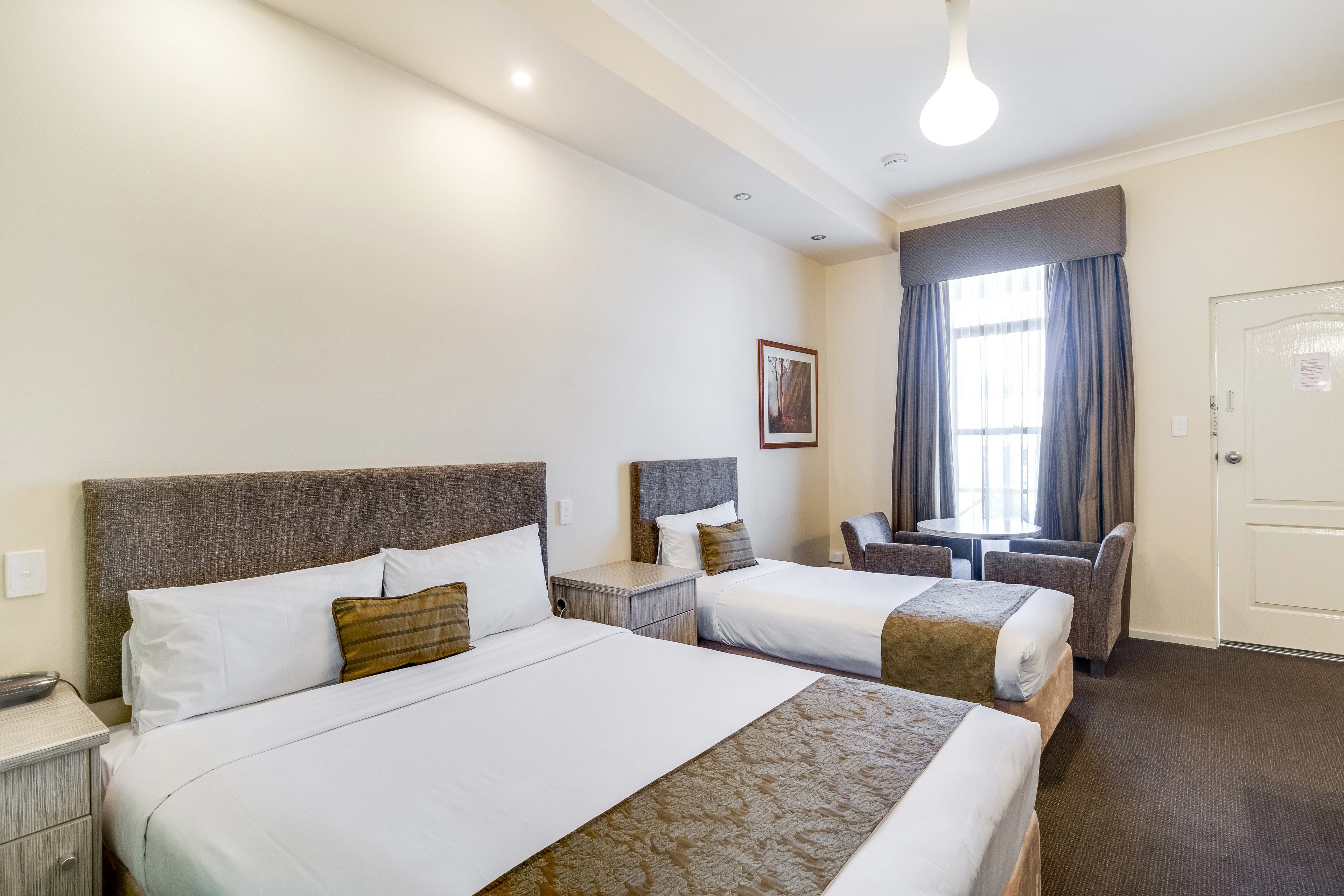 Quarto de hotel com duas camas, uma mesa e uma cadeira.