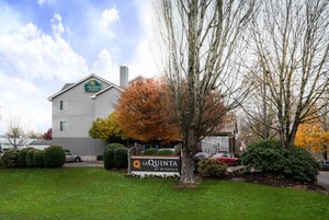 Um hotel com uma placa indicando 'La Quinta by Wyndham', rodeado por jardins bem cuidados e árvores.