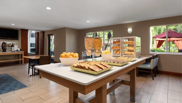 Disposição de buffet de café da manhã com diversas opções de alimentos e área de estar.