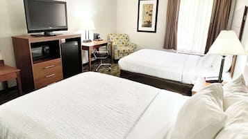 Quarto de hotel com duas camas, uma escrivaninha com computador, televisão e uma cadeira.