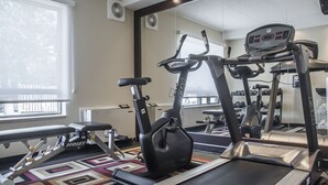 Uma academia com esteiras, um banco e uma máquina de musculação.