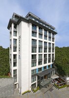Um hotel de vários andares com design moderno, exibindo uma placa chamativa do 'Arcadia Hotel' e um restaurante no andar térreo.
