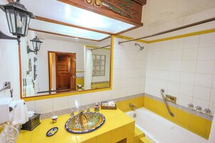 Uma casa de banho com uma pia amarela, uma banheira e um espelho grande.