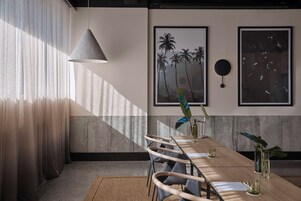 Uma área de refeições moderna com uma mesa de madeira comprida, cadeiras e um lustre.