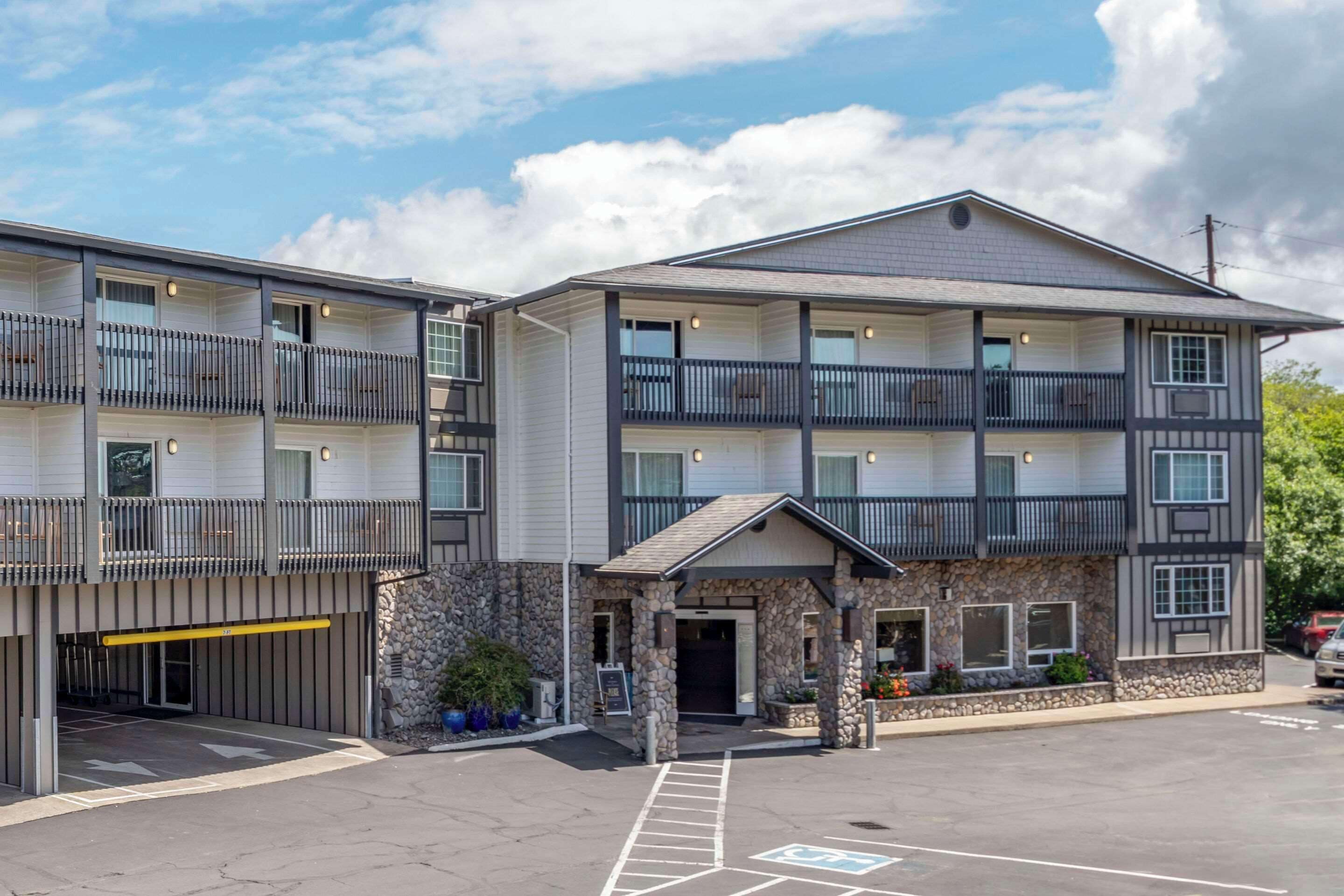 Um hotel com vários andares, varandas, fachada de pedra e estacionamento.