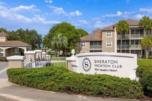 Placa do Sheraton Vacation Club PGA Vacation Resort, com entrada por portão e vegetação ao redor.