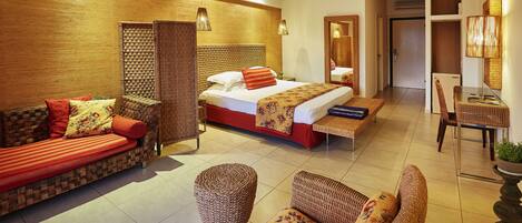 Quarto de hotel com cama, sofá, cadeira e mesa pequena.