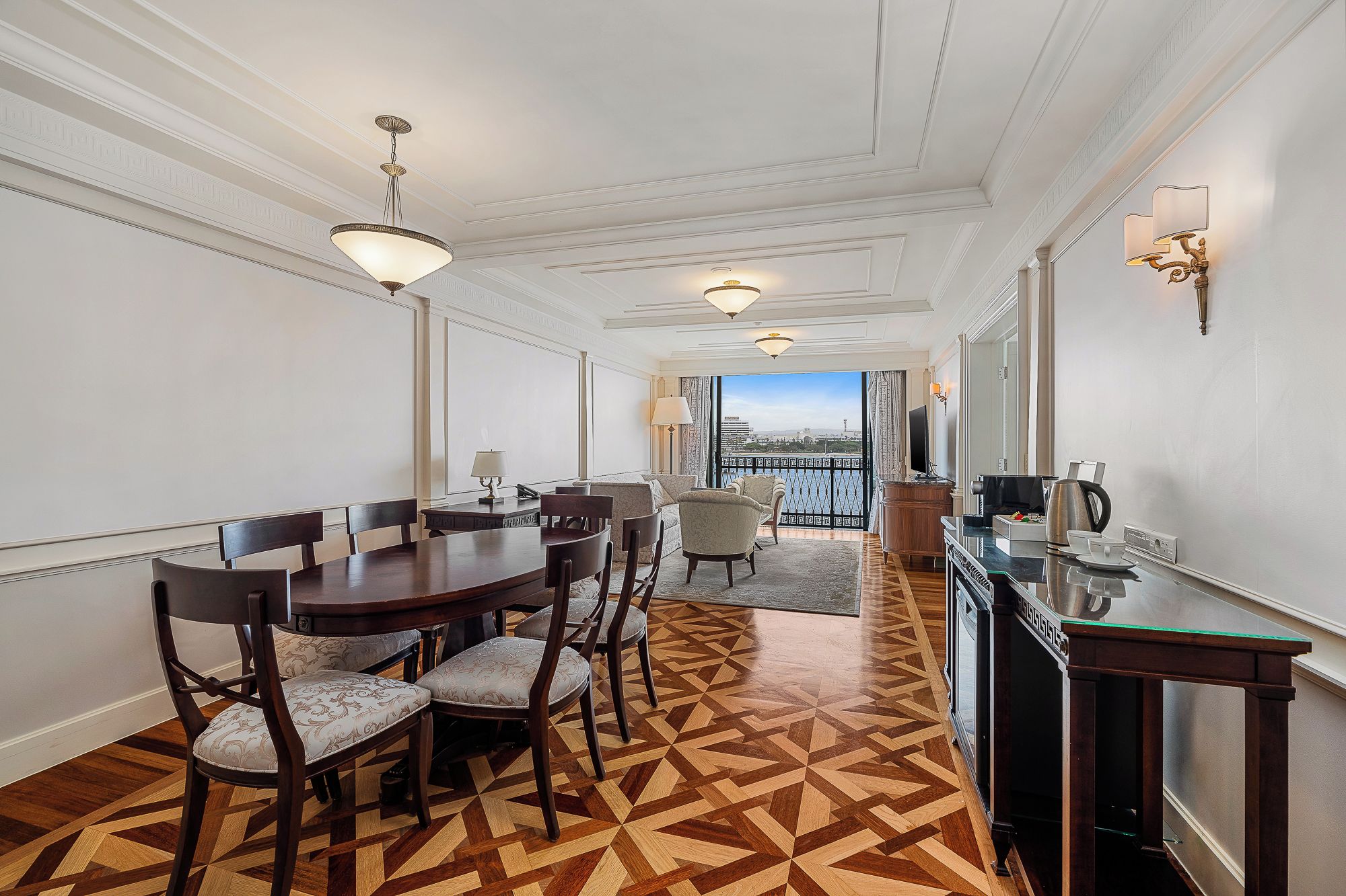 Quarto de hotel com área de refeições, espaço de estar, varanda com vista para a cidade e cozinha compacta.