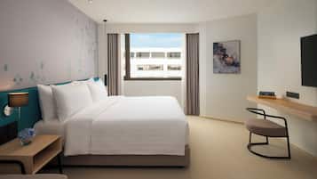 Quarto de hotel moderno com cama, escrivaninha, cadeira, televisão e janela com vista para a cidade.