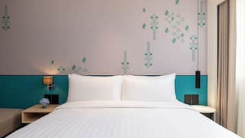 Quarto de hotel com cama, mesa de cabeceira com abajur, luminária na parede e janela com cortinas.