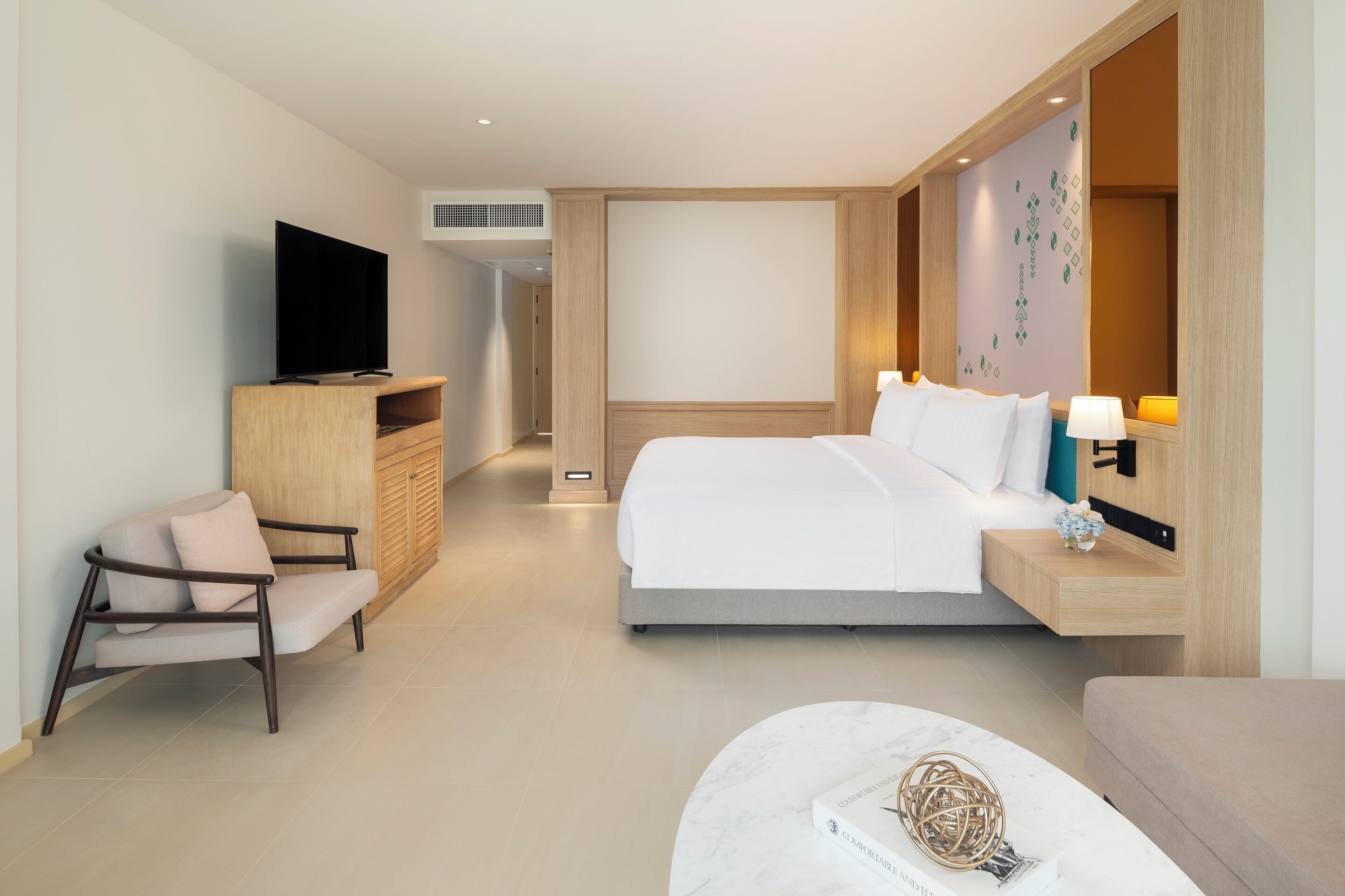 Quarto de hotel moderno com cama, televisão, secretária e cadeira.