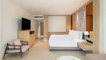 Quarto de hotel moderno com cama, televisão, secretária e cadeira.