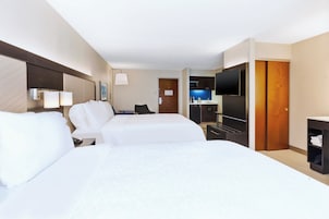 Quarto de hotel com duas camas, uma escrivaninha, televisão, minibar e banheiro.