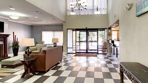 Um saguão com piso xadrez, um sofá, um abajur e um candelabro.