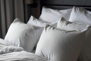 Uma cama com roupa de cama e almofadas brancas.