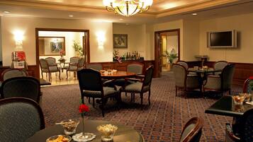 Uma sala de jantar de hotel com um candelabro, várias mesas e cadeiras.