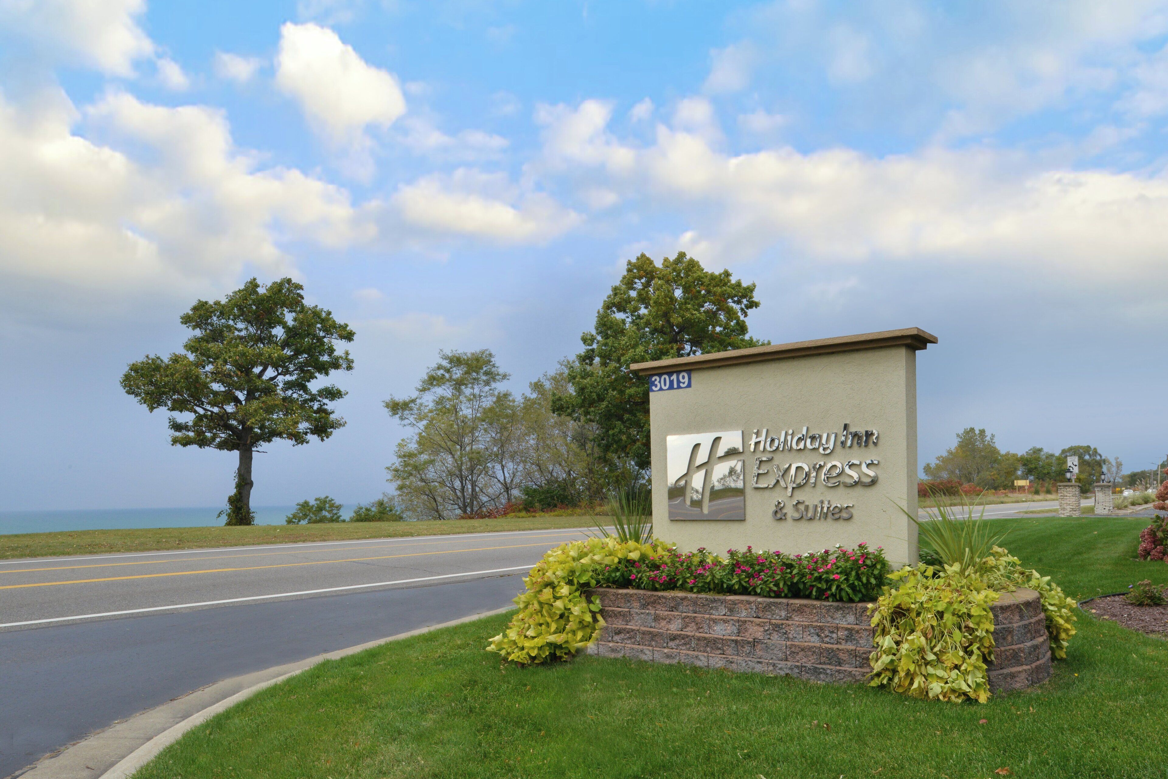 Placa da Holiday Inn Express & Suites, com vista para a estrada e árvores.