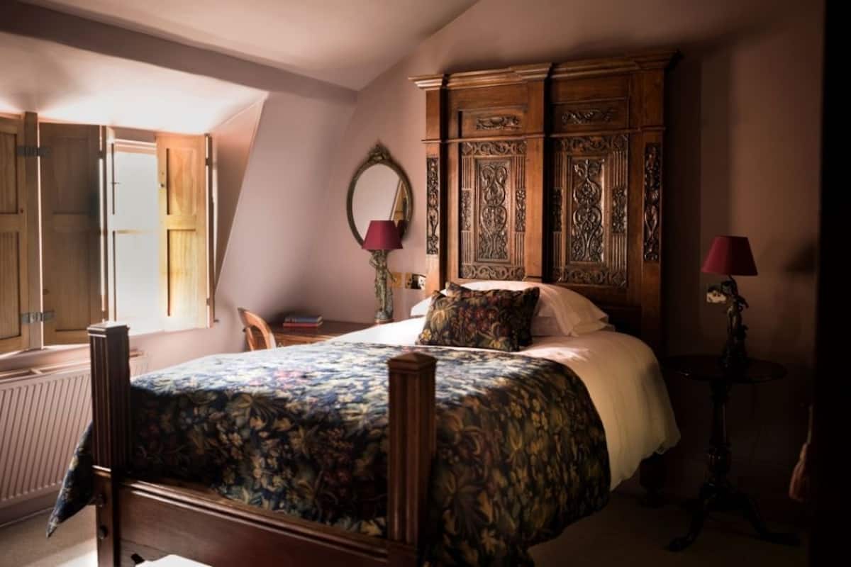 Um quarto com uma cama de madeira, um espelho grande e um guarda-roupa.