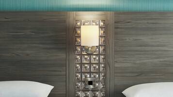 Quarto de hotel com cama, mesa de cabeceira, luminária fixada na parede e quadro emoldurado.