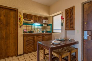 Uma cozinha compacta com armários de madeira, micro-ondas e mesa de jantar com cadeiras.
