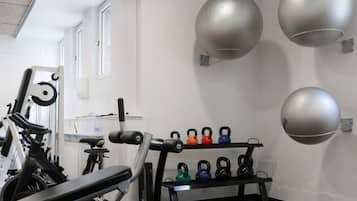Uma academia com equipamentos de exercício, kettlebells e bolas de medicina fixadas na parede.